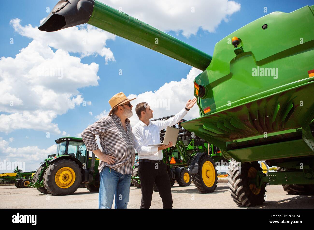 Professional farmer with a modern combine at field in sunlight at work ...