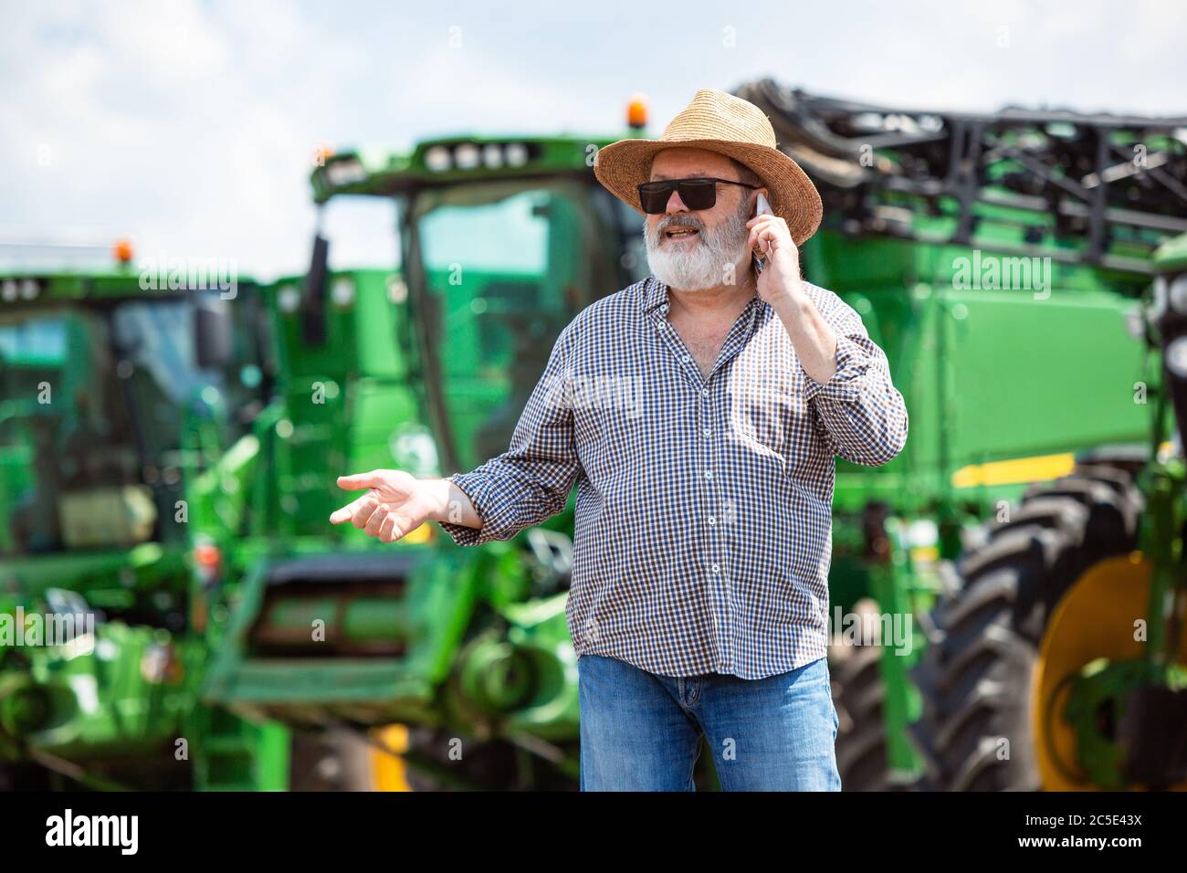 Professional farmer with a modern tractor at work talking phone. Looks ...