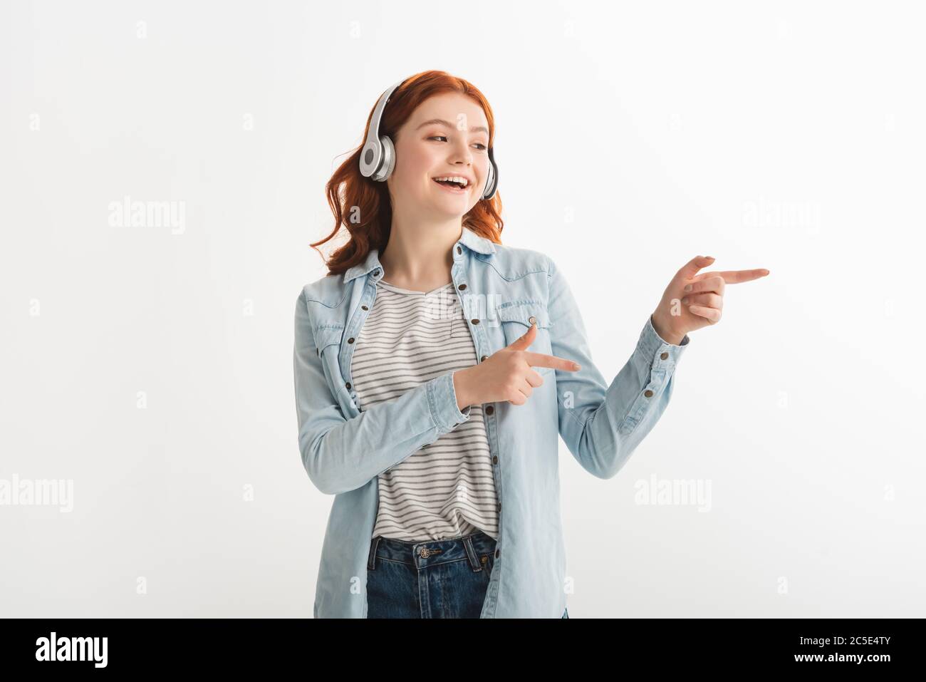 excited teen girl listening music with headphones and pointing isolated ...