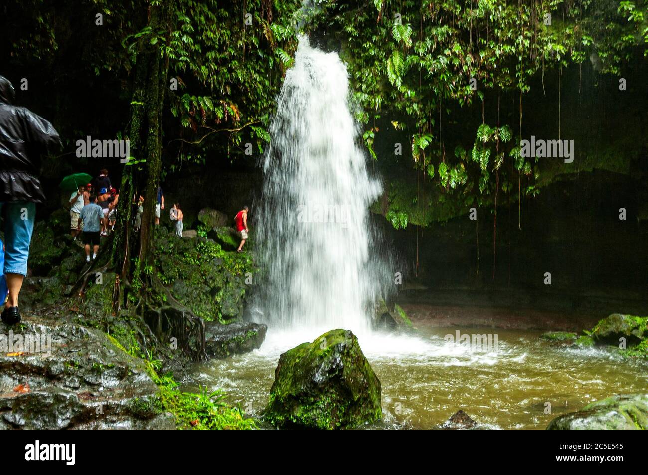 Tourists stop on a narrow track in heavy rain to admire a waterfall ...