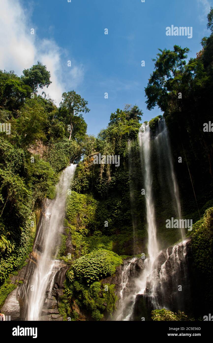 A vertical image of Sekumpul Waterfall with the clear blue sky in Bali ...