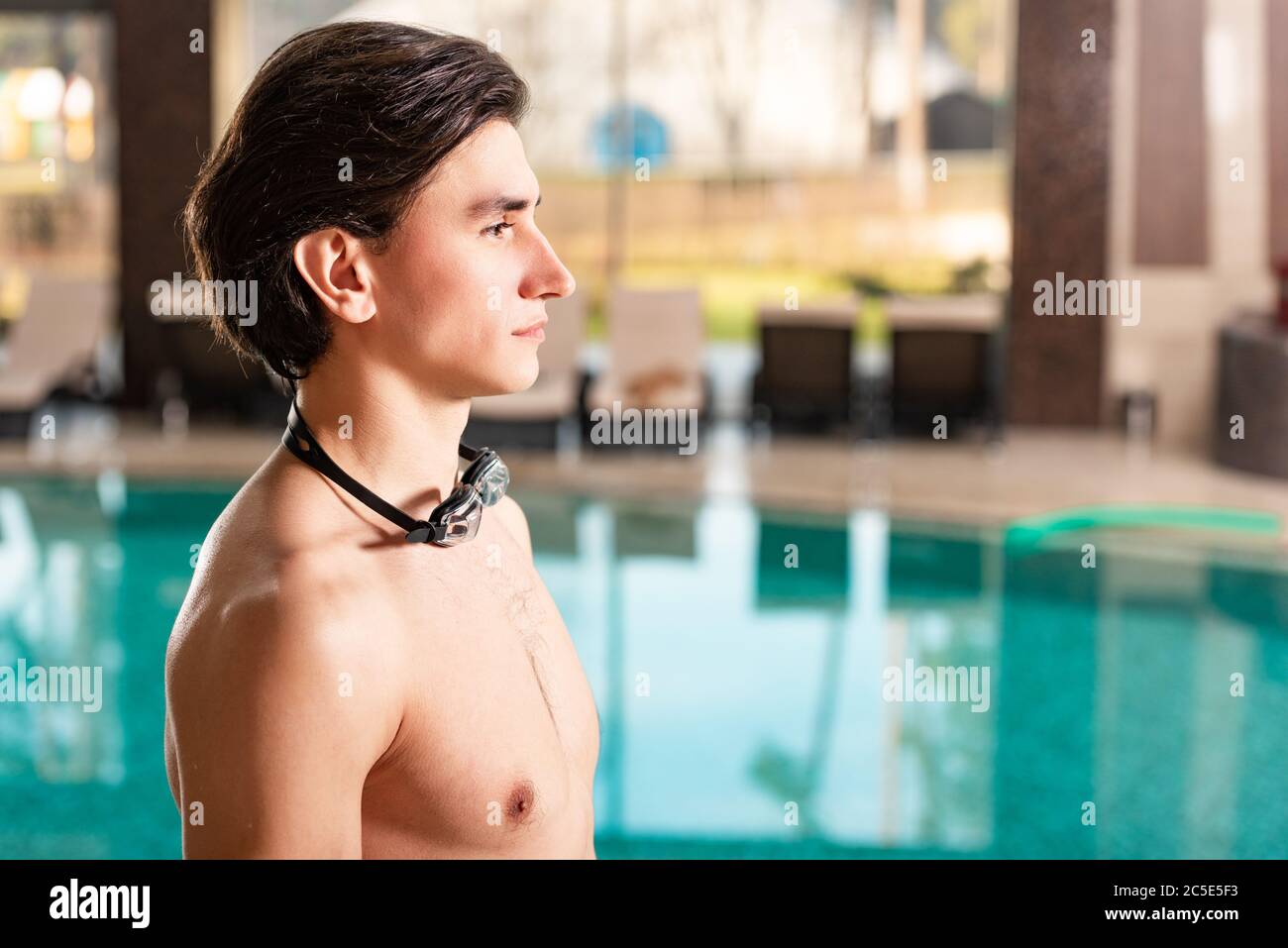 Side view of handsome man in swimming googles looking away near ...