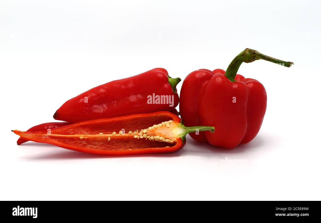 Few red ripe sweet peppers and one pepper in a cut on a light ...