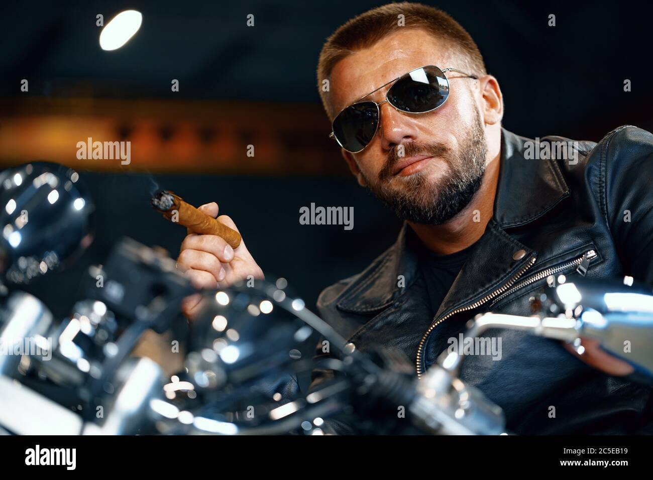 Cool bearded man biker in sunglasses sitting on his motorbike and ...