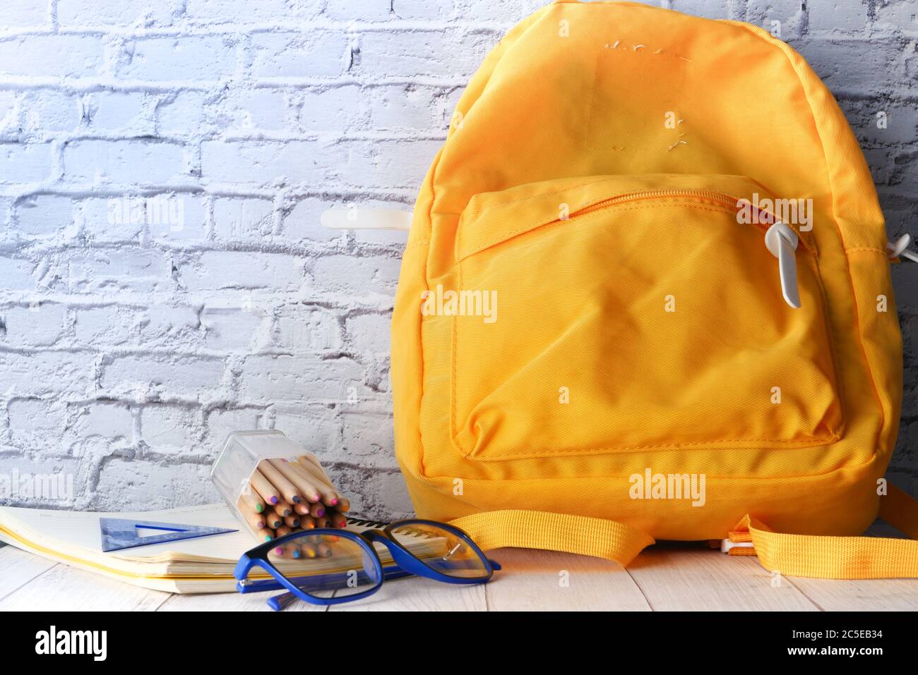 Back to school concept yellow backpack on table Stock Photo - Alamy