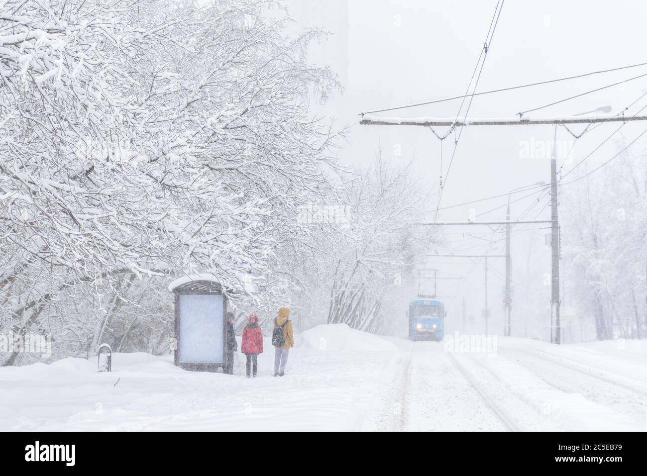 Tram goes during snowstorm in winter, Moscow, Russia. People wait the ...