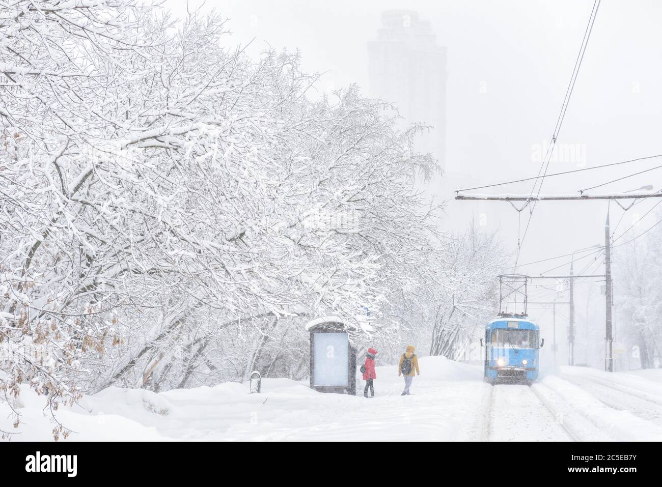 Tram goes during snowstorm in winter, Moscow, Russia. People wait the ...