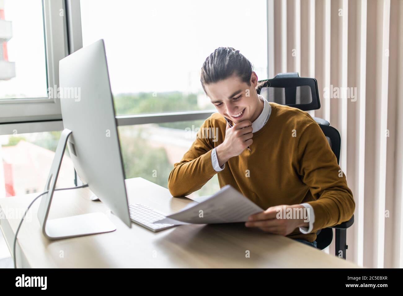 Young businessman writing notes in front on pc monitor sitting at a ...