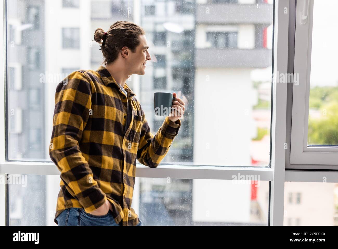Young man looking out his window at home in the kitchen Stock Photo - Alamy