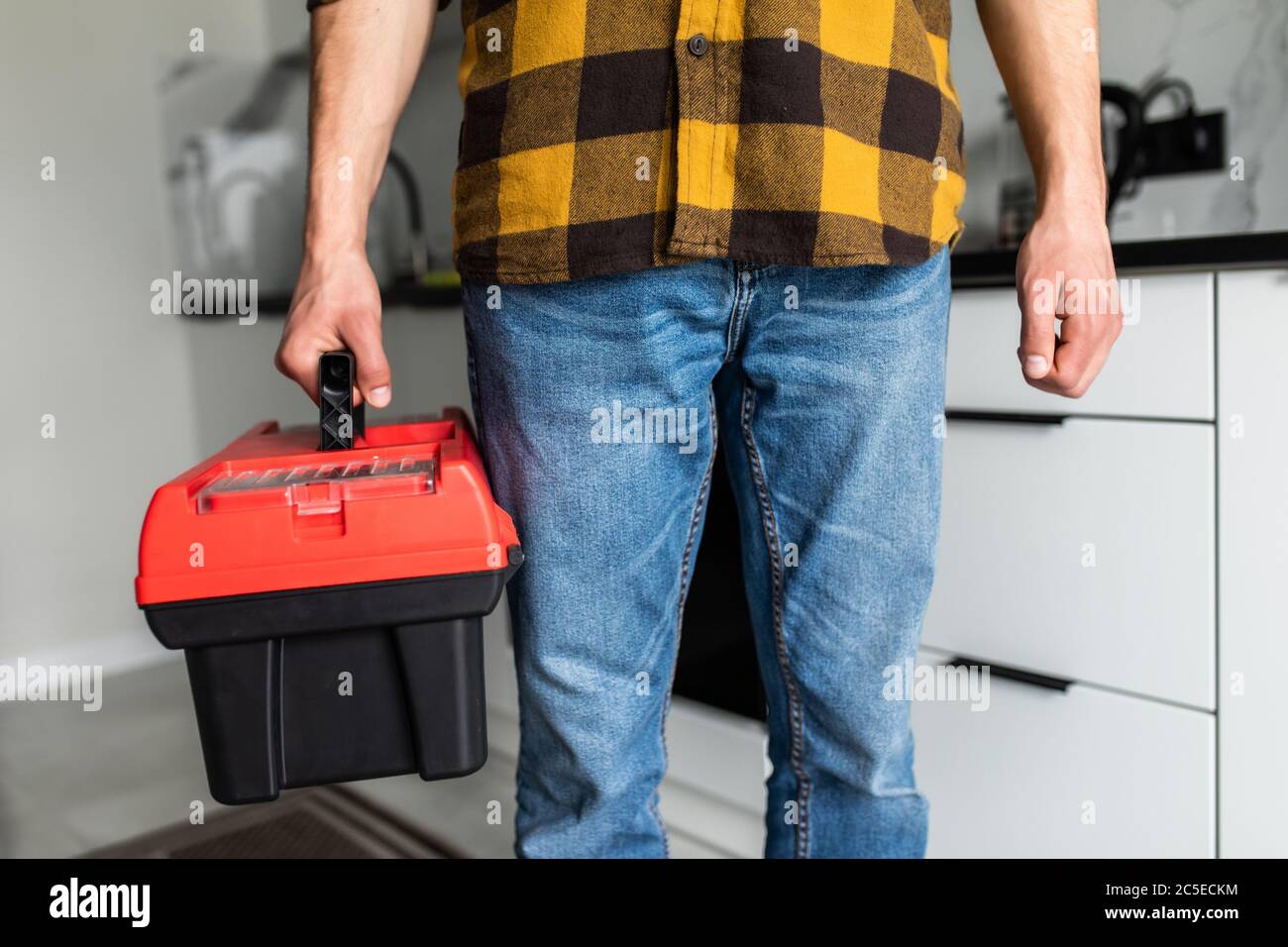 Close up man plumber holding toolbox in the kitchen a prepare for work ...
