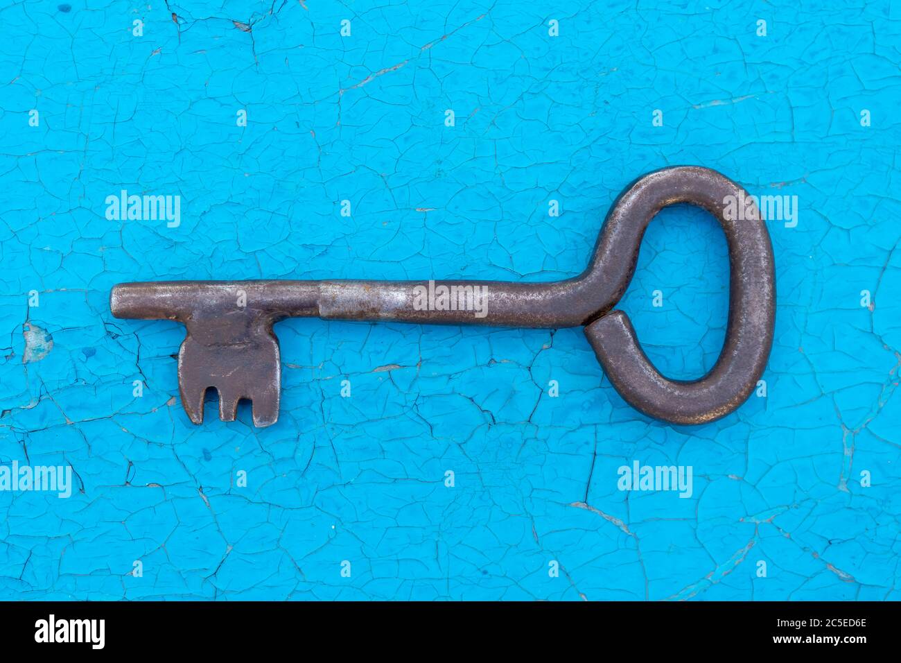 Old iron key isolated on blue background Stock Photo - Alamy