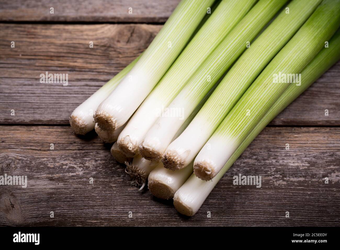 Baby leeks on old wood background, vintage style with intentional ...