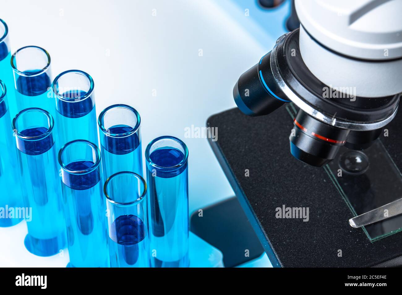 Close up of laboratory microscope with set of test tubes with blue ...