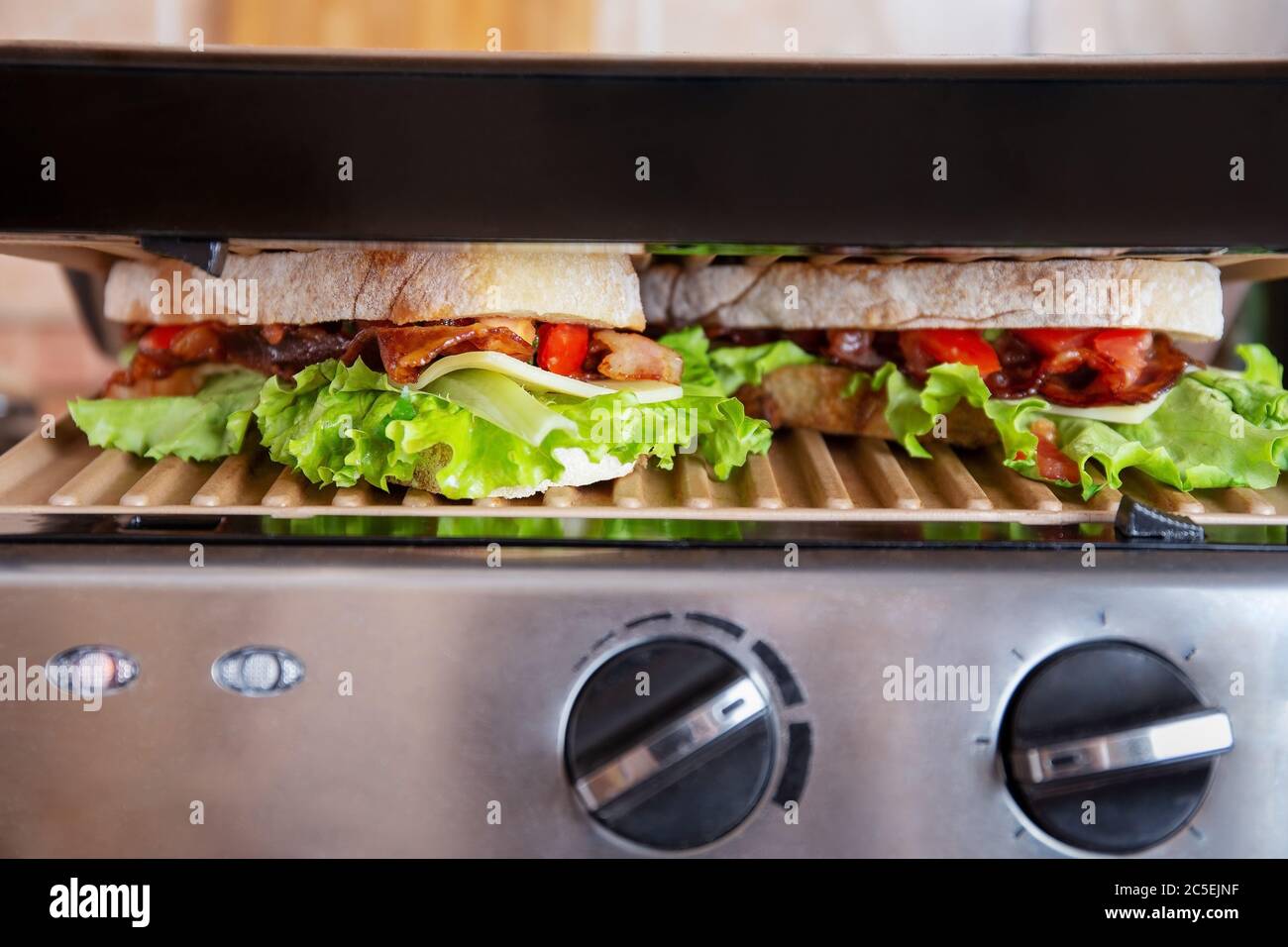 A sandwich or long panini stuffed with lettuce, tomato and cheese with ...