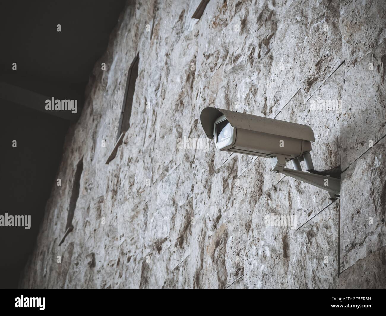 The surveillance camera is mounted on a wall with narrow windows and ...