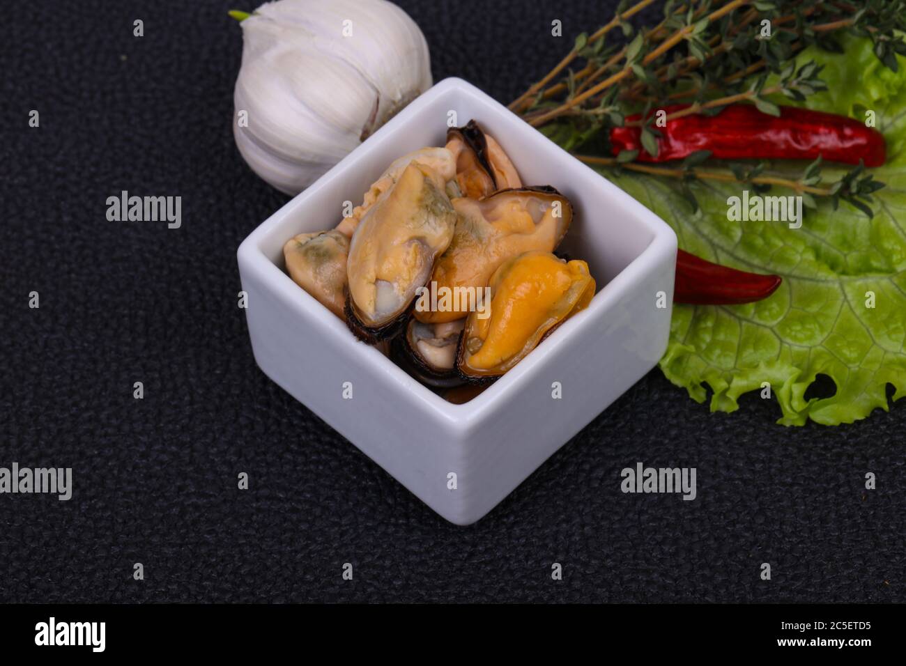 Pickled mussels in the bowl served pepper, garlic and salad leaves ...