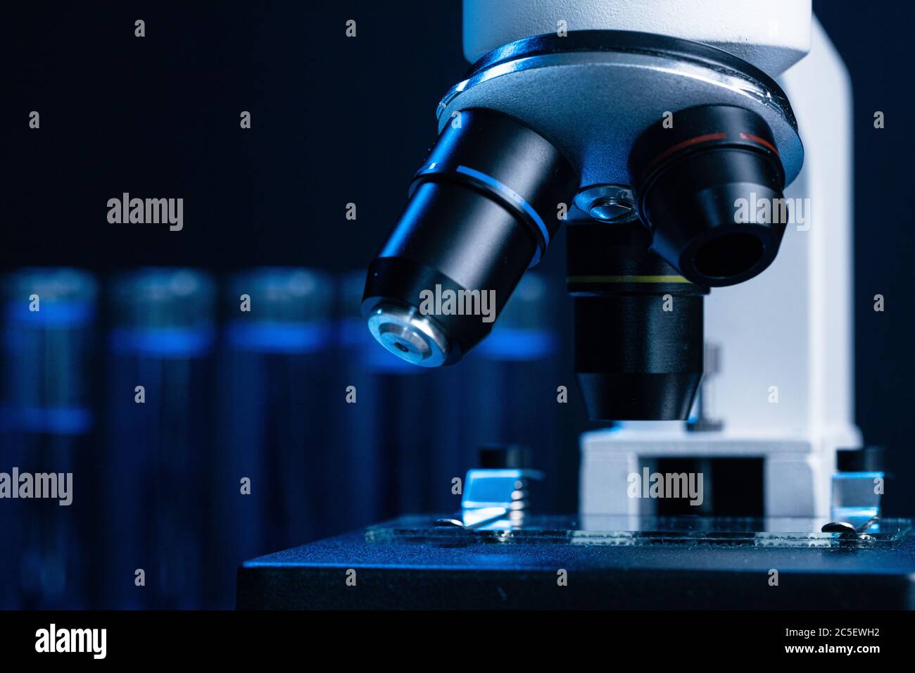 Close up of laboratory microscope with set of test tubes with blue ...