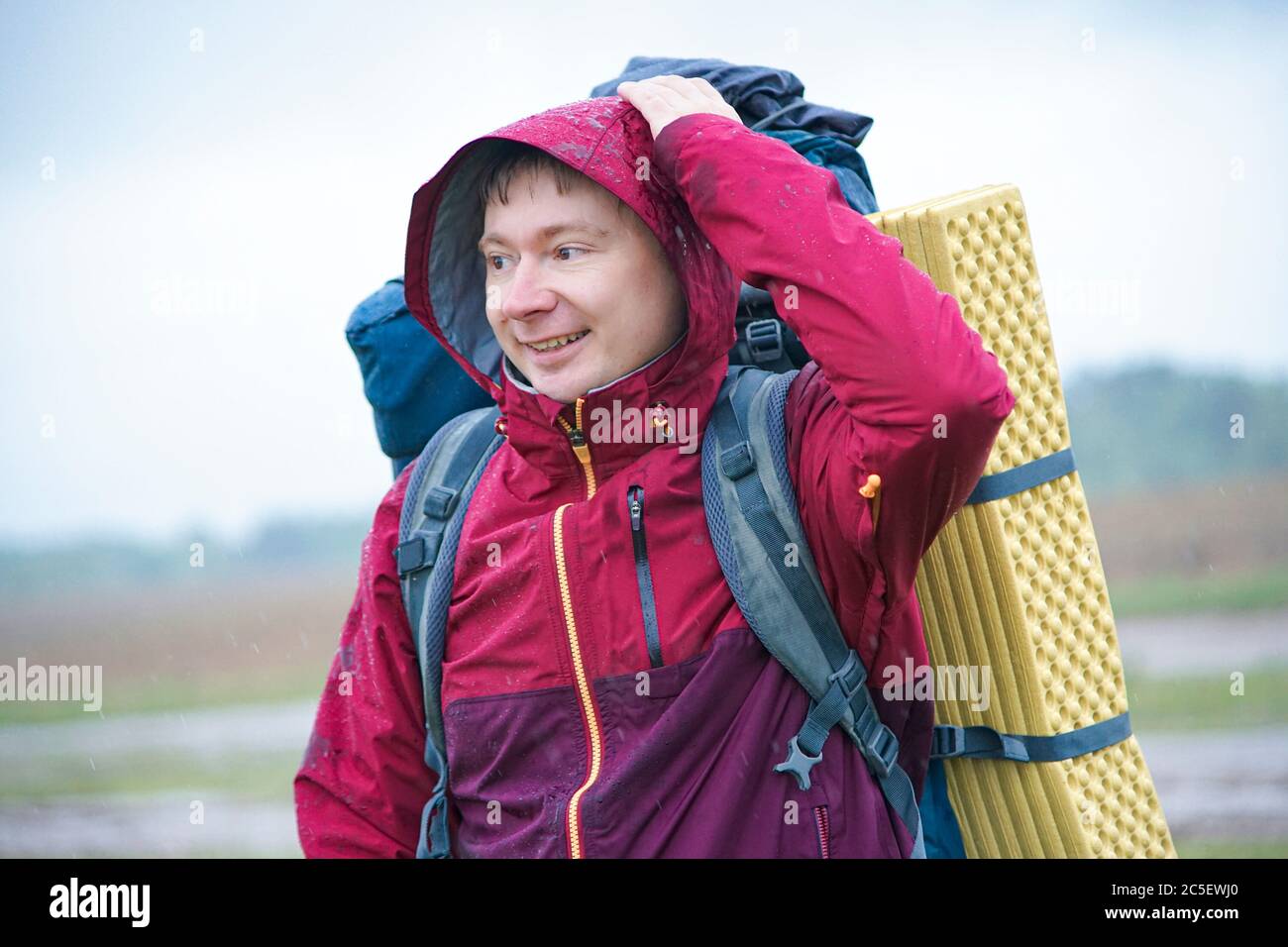 The guy is in the rain in a jacket. He looks up and smiles in the rain ...