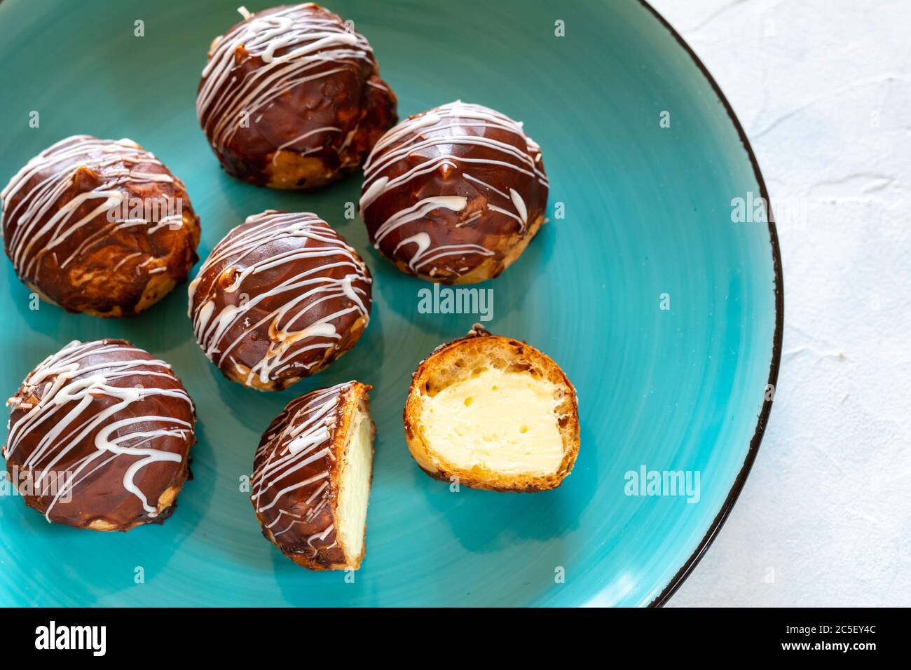 Mini puff cakes with vanilla pudding topped with chocolate Stock Photo ...