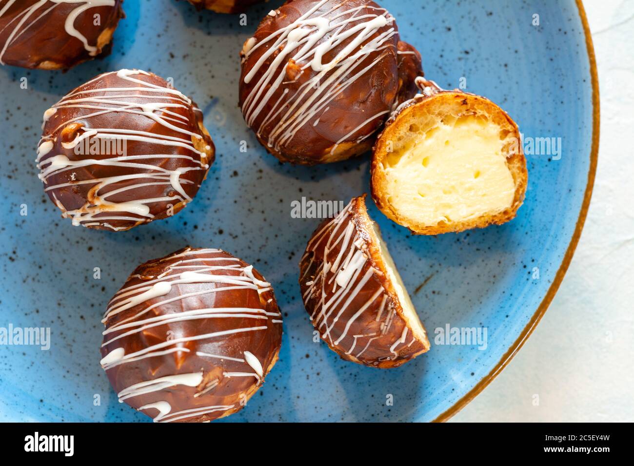 Mini puff cakes with vanilla pudding topped with chocolate Stock Photo ...
