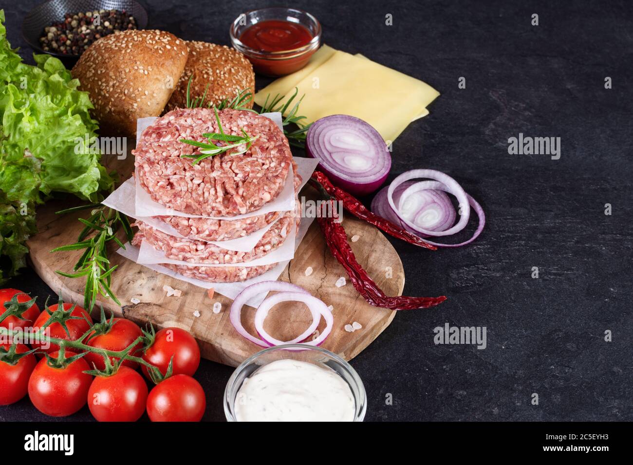 Fresh raw ingredients for homemade burger on black background ...