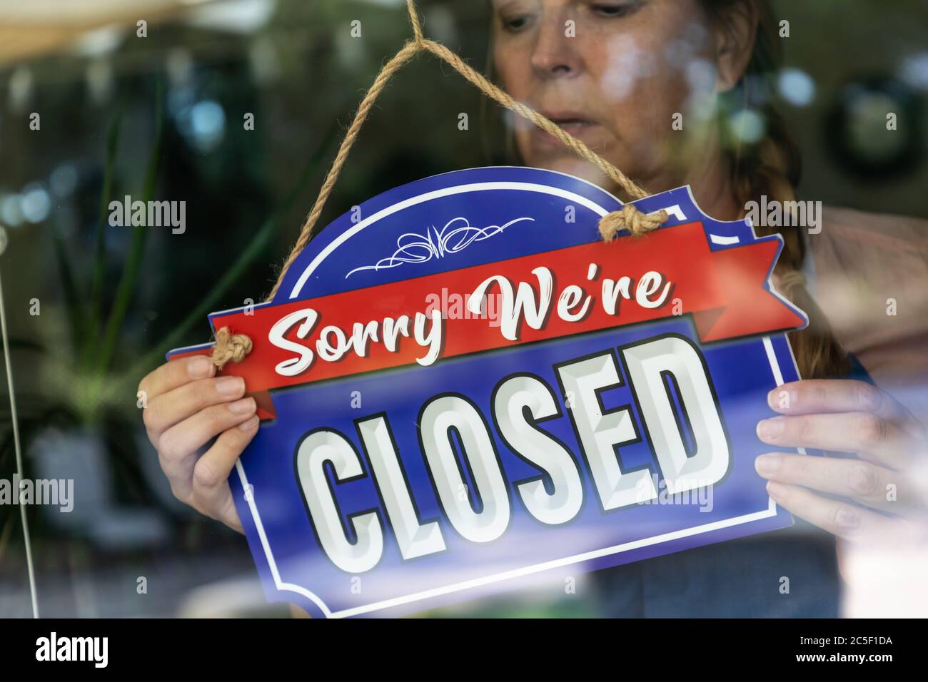 Sad Female Store Owner Turning Sign to Closed in Window Stock Photo - Alamy