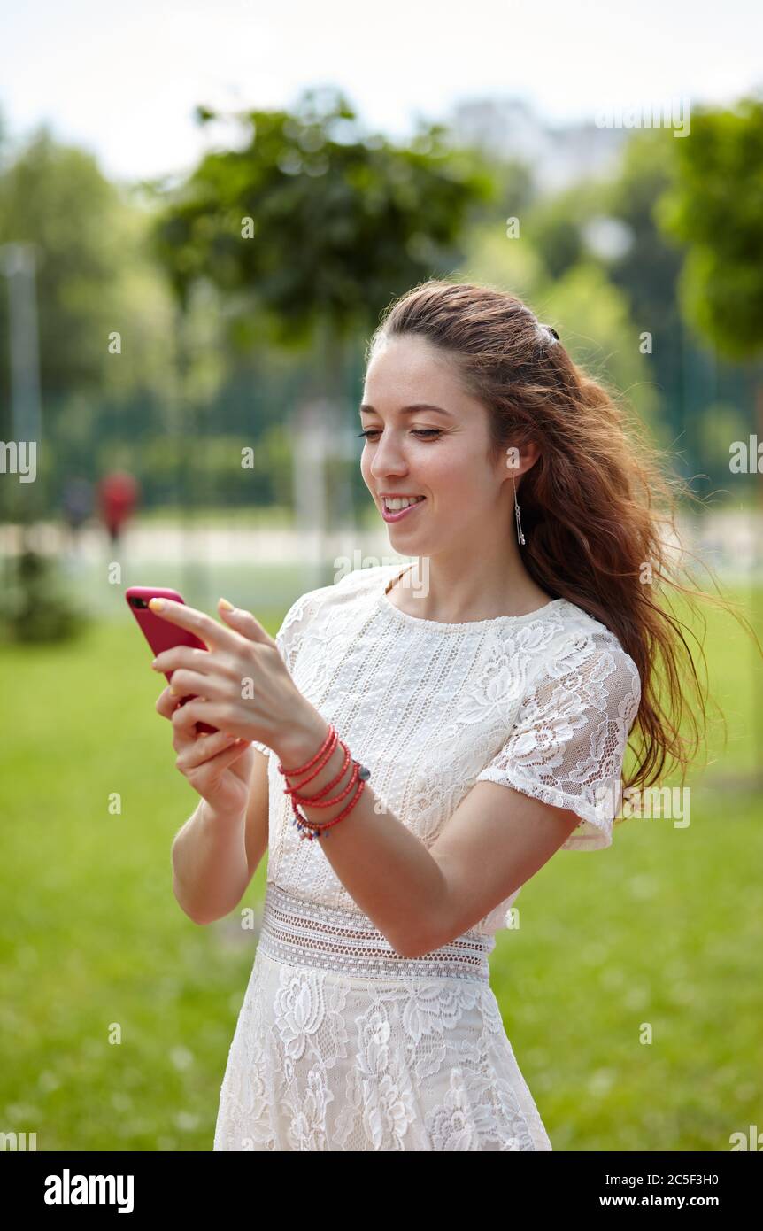 Young Woman In Dress Holding Mobile Phone In Summer Park Caucasian