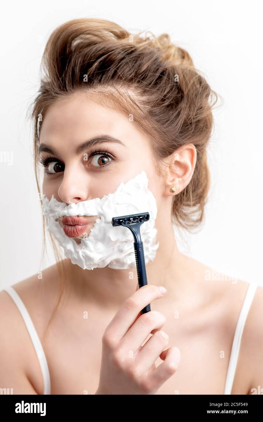 Beautiful young caucasian woman shaving her face by razor on white ...