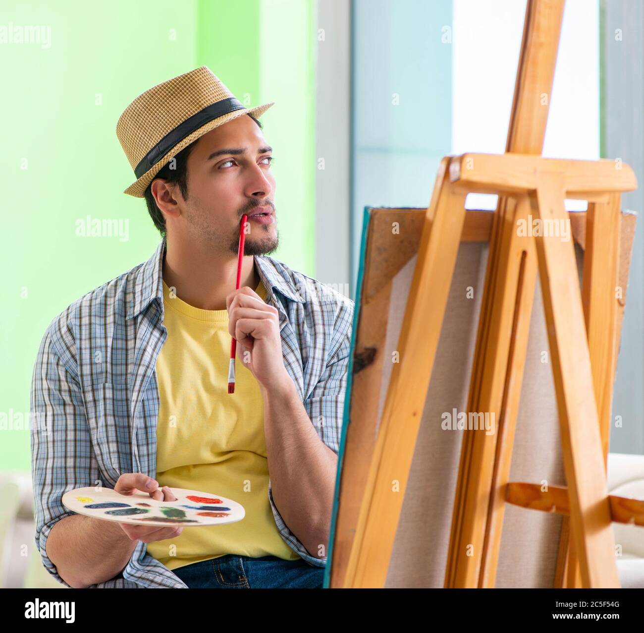 The young male artist working on new painting in his studio Stock Photo ...