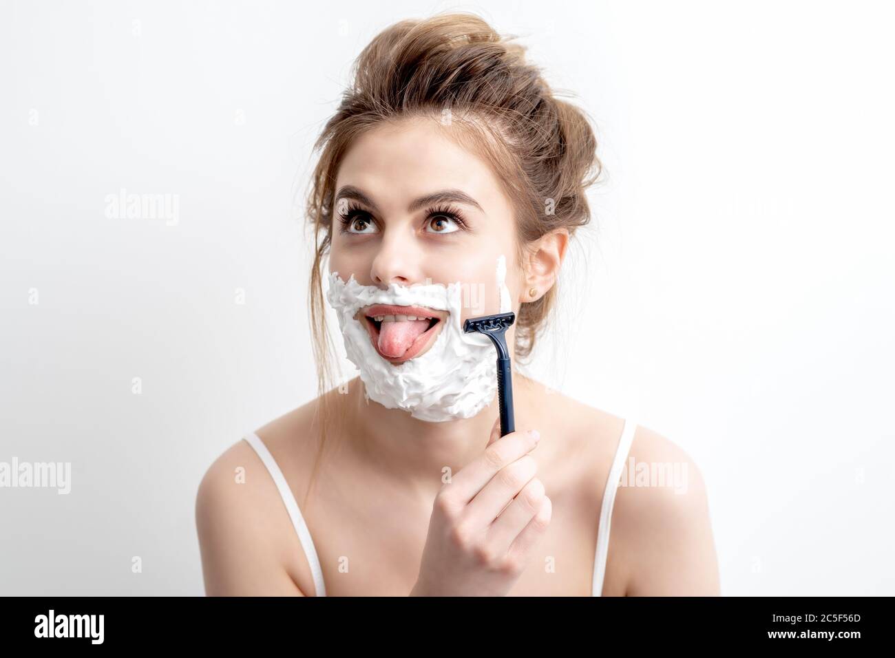 Beautiful young caucasian woman shaving her face by razor on white ...