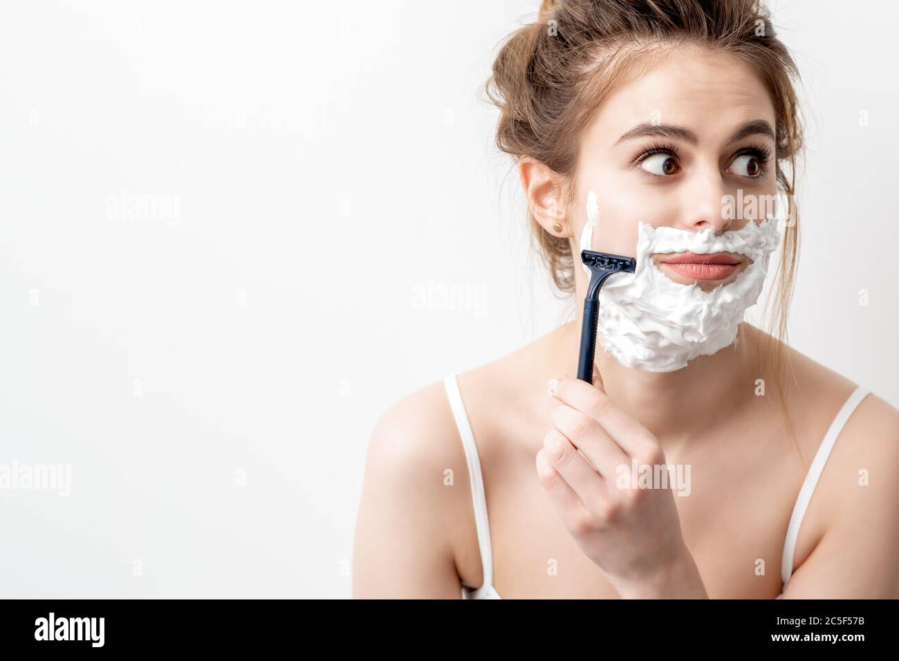 Beautiful young caucasian woman shaving her face by razor on white ...
