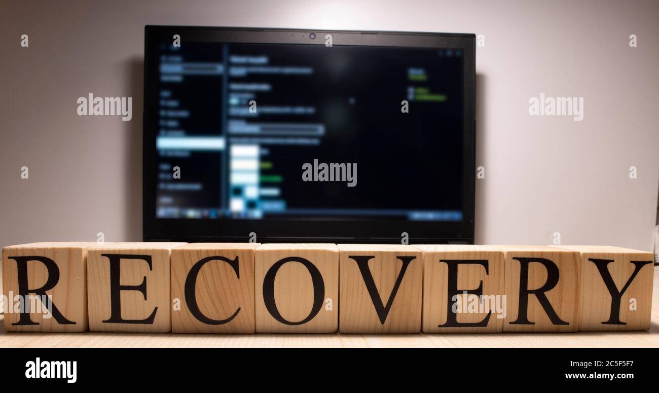 Recovery word from wooden cubes on laptop Stock Photo - Alamy