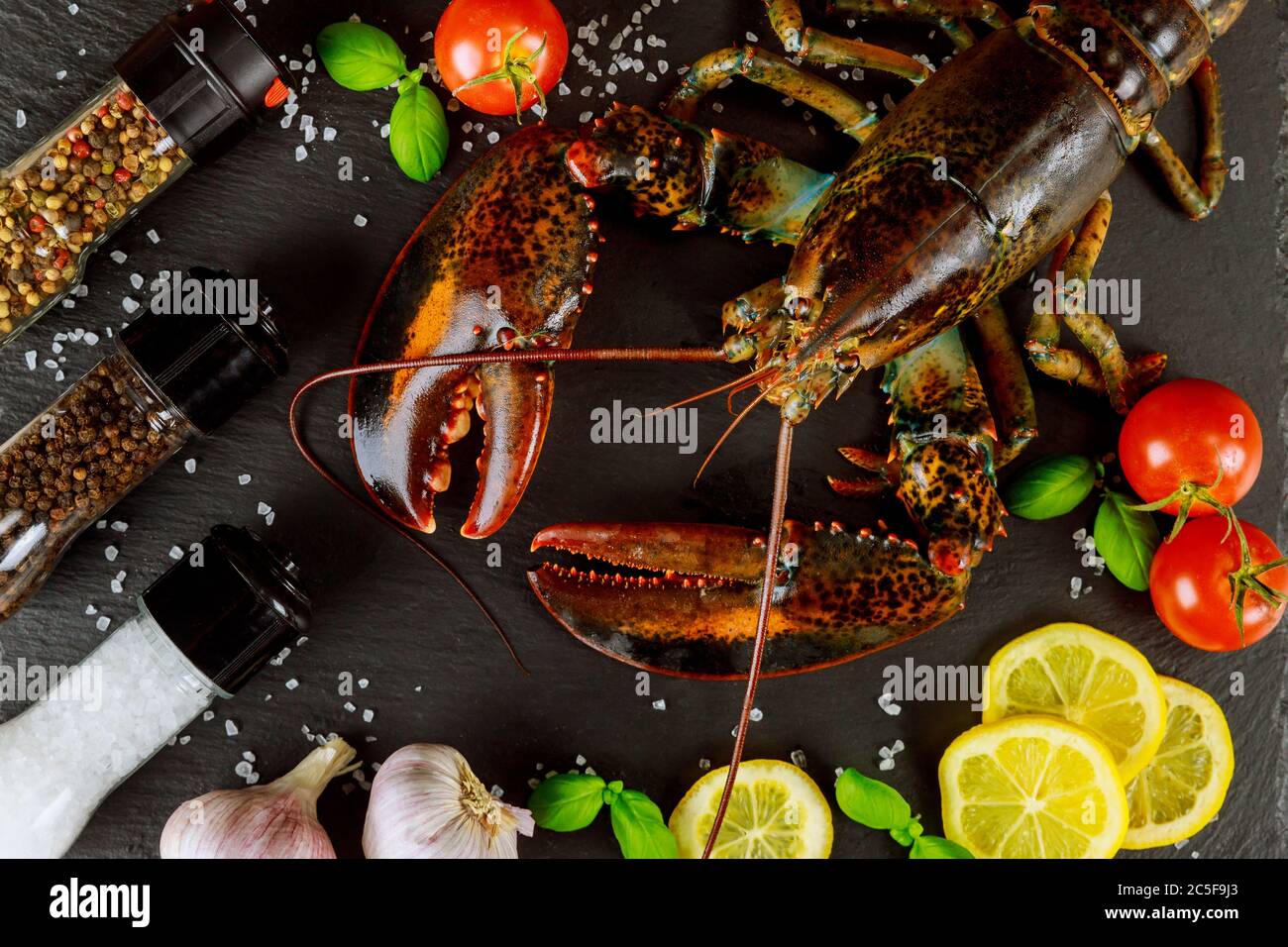 Raw uncooked lobster on black board with spices and vegetables. Top ...
