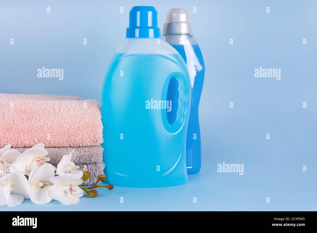 Bottles of detergent and fabric softener with clean towels and orchid ...