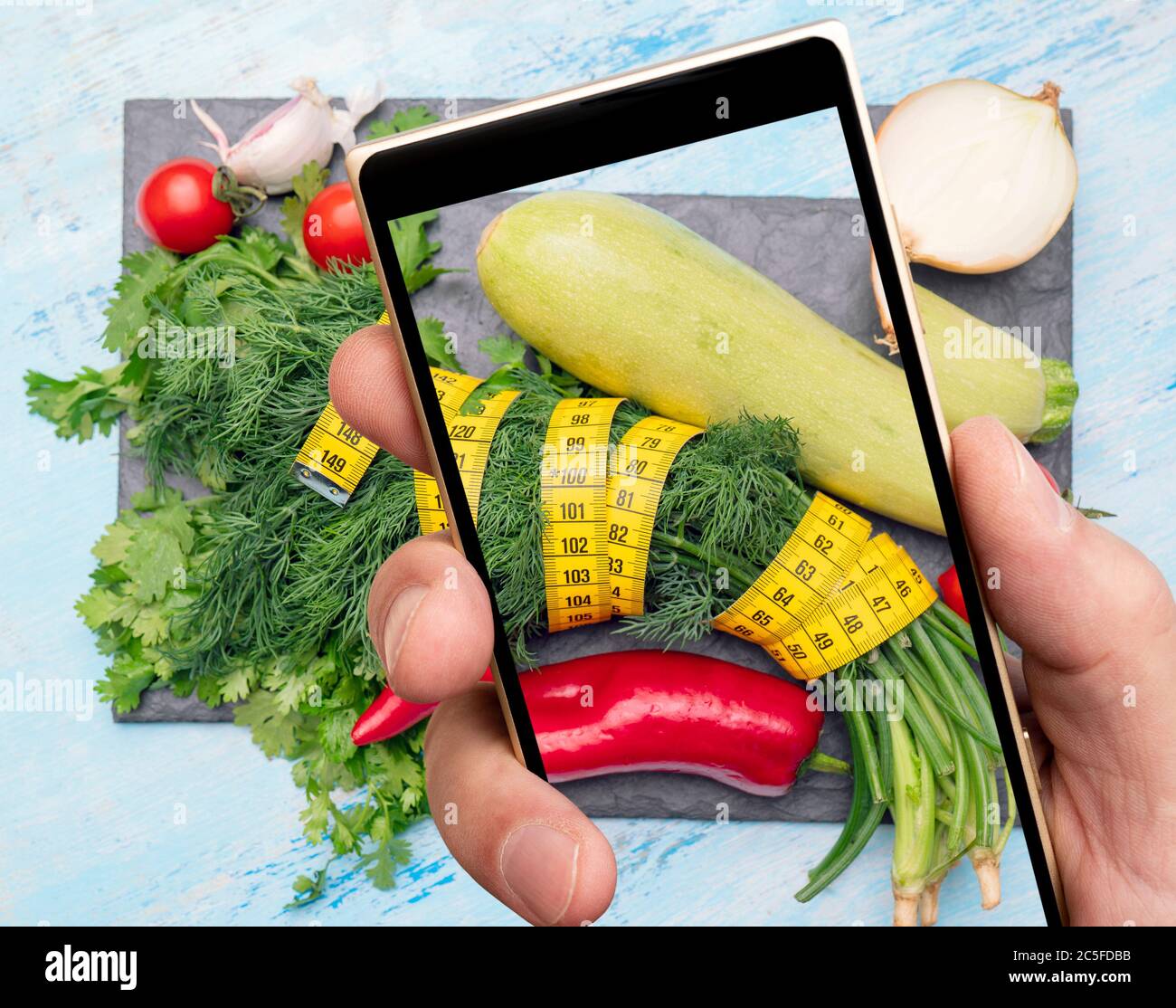Vegetables for diet cooking on smartphone screen. Measuring tape for ...