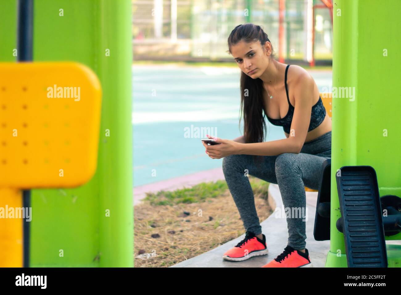 Mexican fitness girl texting in an outdoor gym in fitness clothes Stock ...
