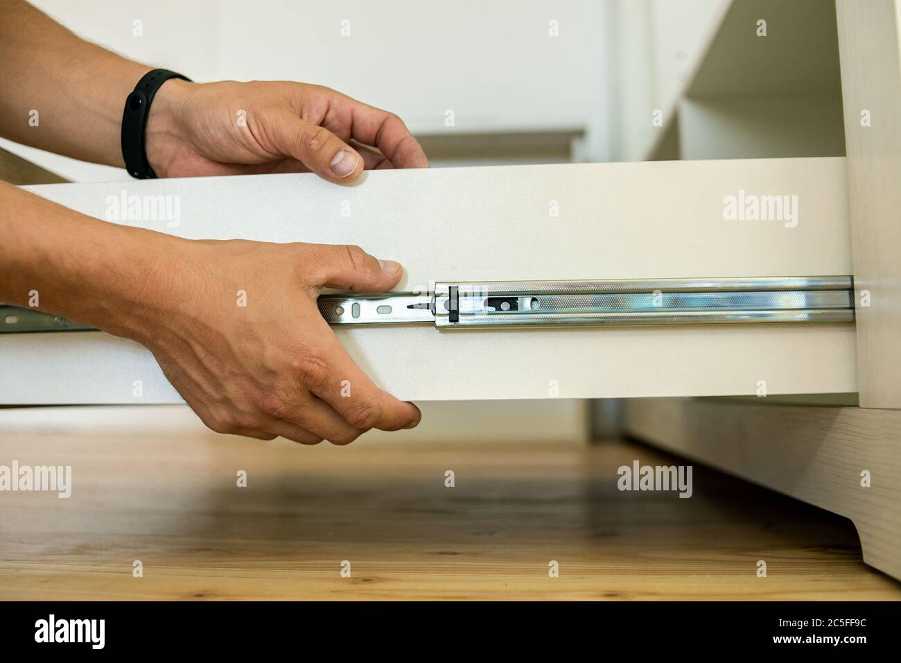 Close up of carpenter hands installing wooden drawer on sliding skids ...