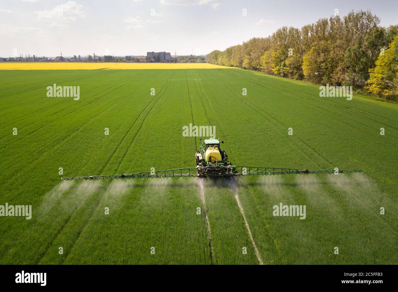 Tractor spraying chemical pesticides with sprayer on the large green ...