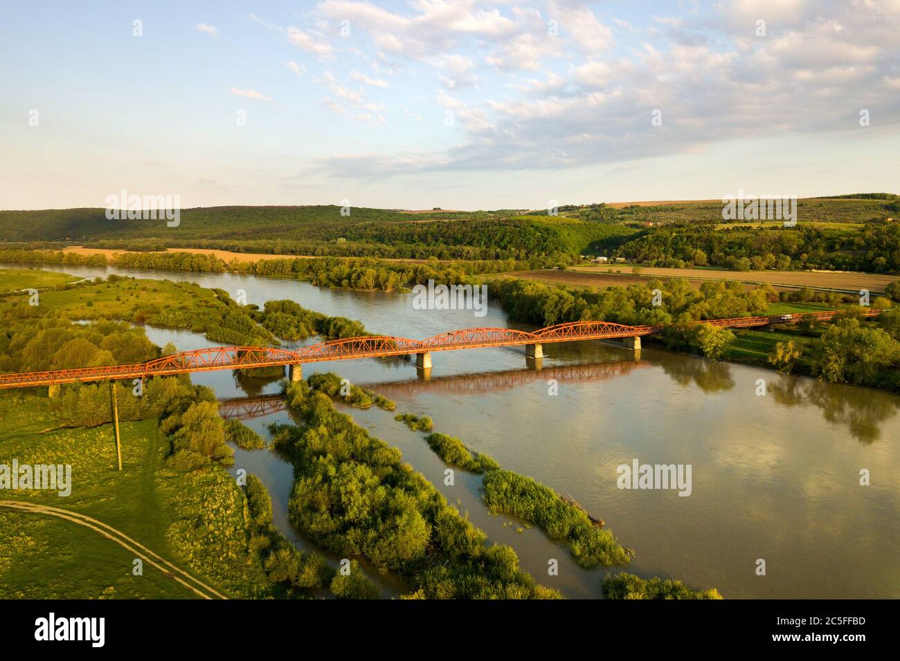 Aerial view of a narrow road bridge stretching over muddy wide river in ...