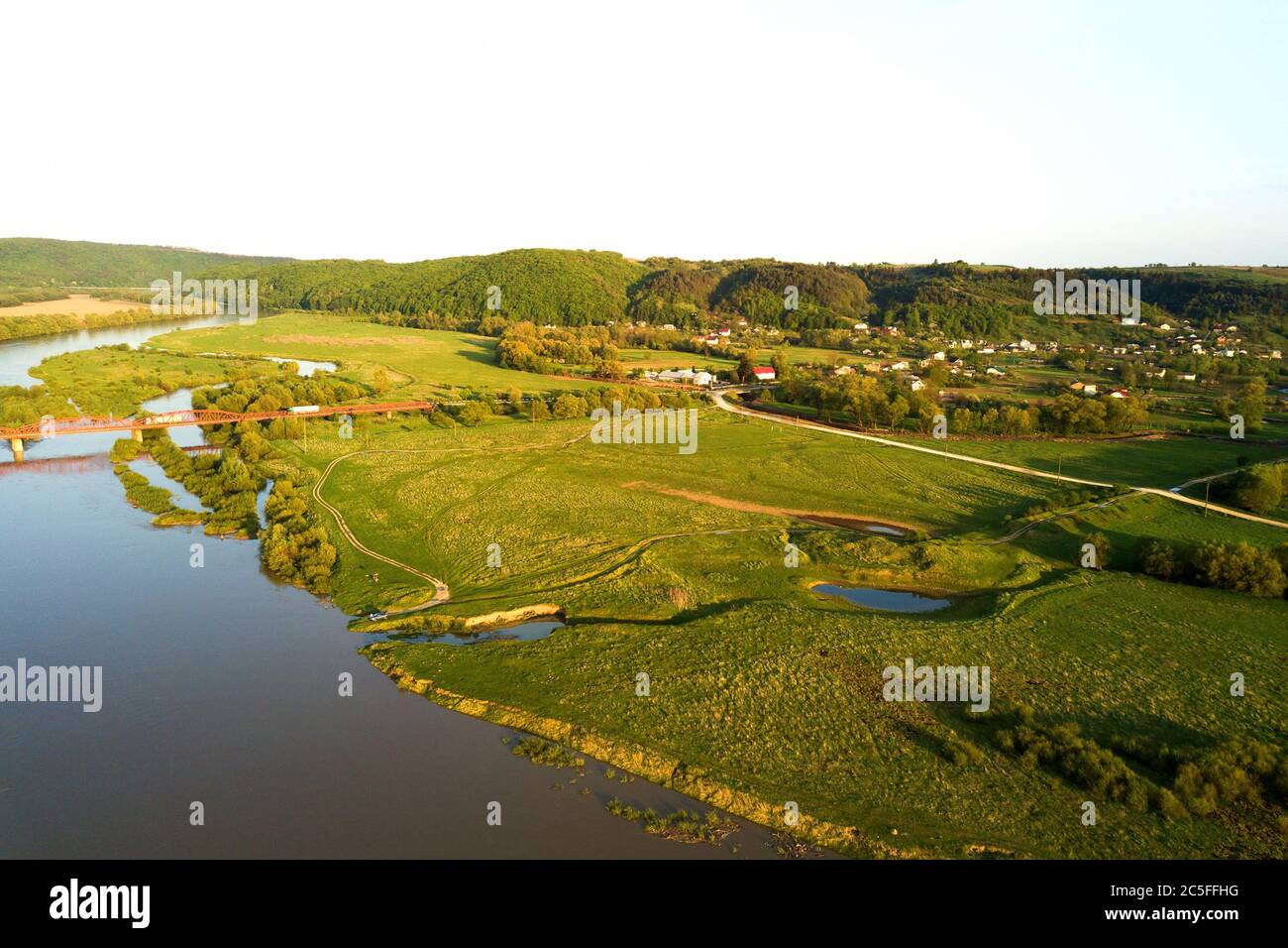 Aerial view of bright river flowing through green meadows in spring ...