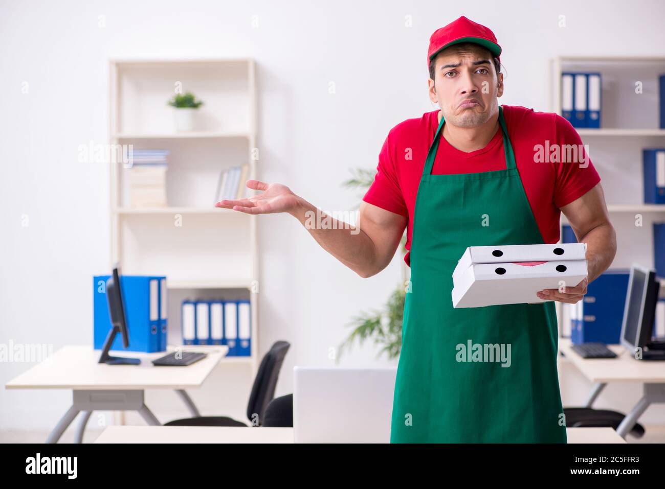 Young courier delivering pizza to the office Stock Photo - Alamy