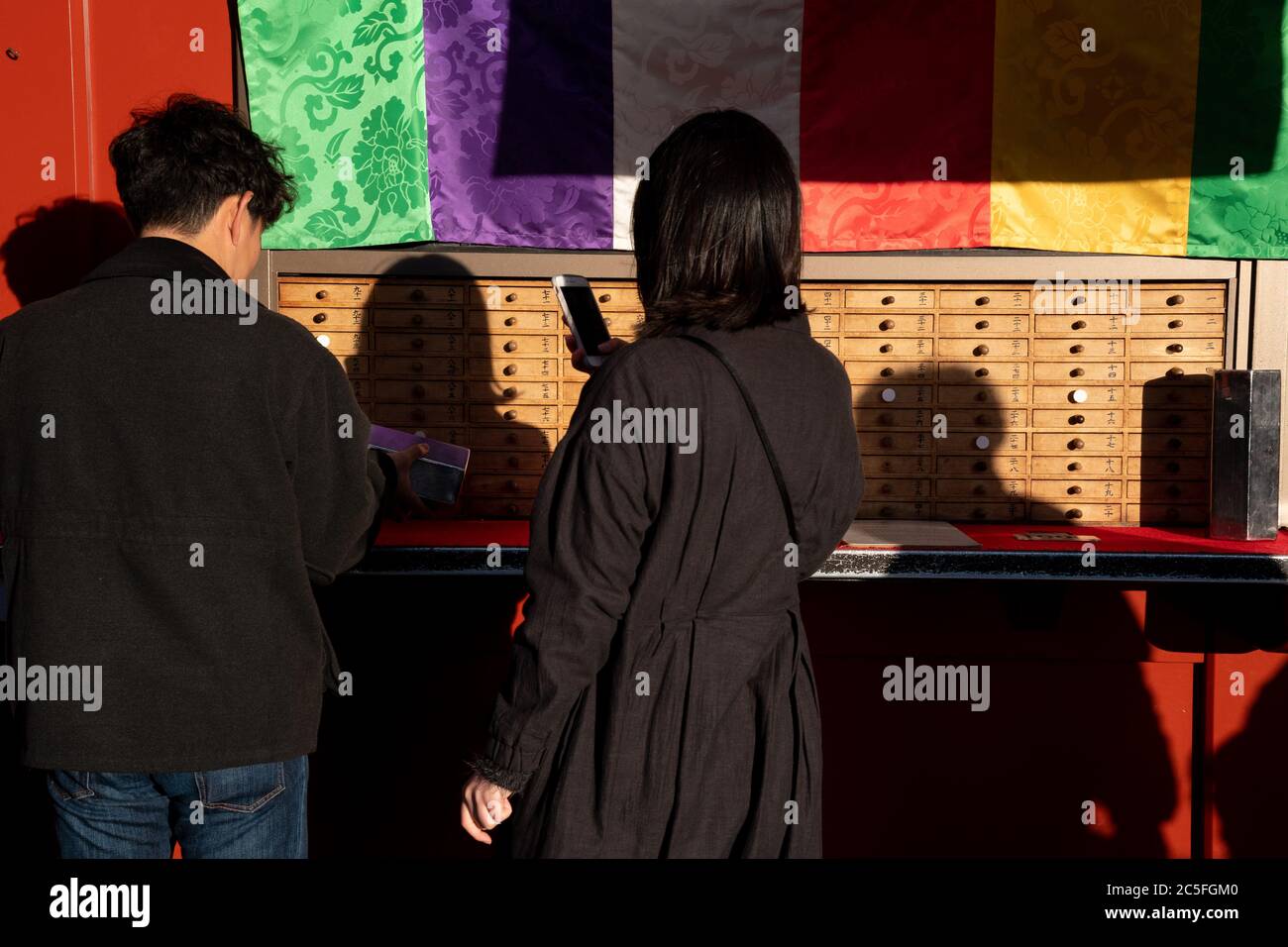 Two friends taking a "o-mikuji" (random prophecies written on strips of ...