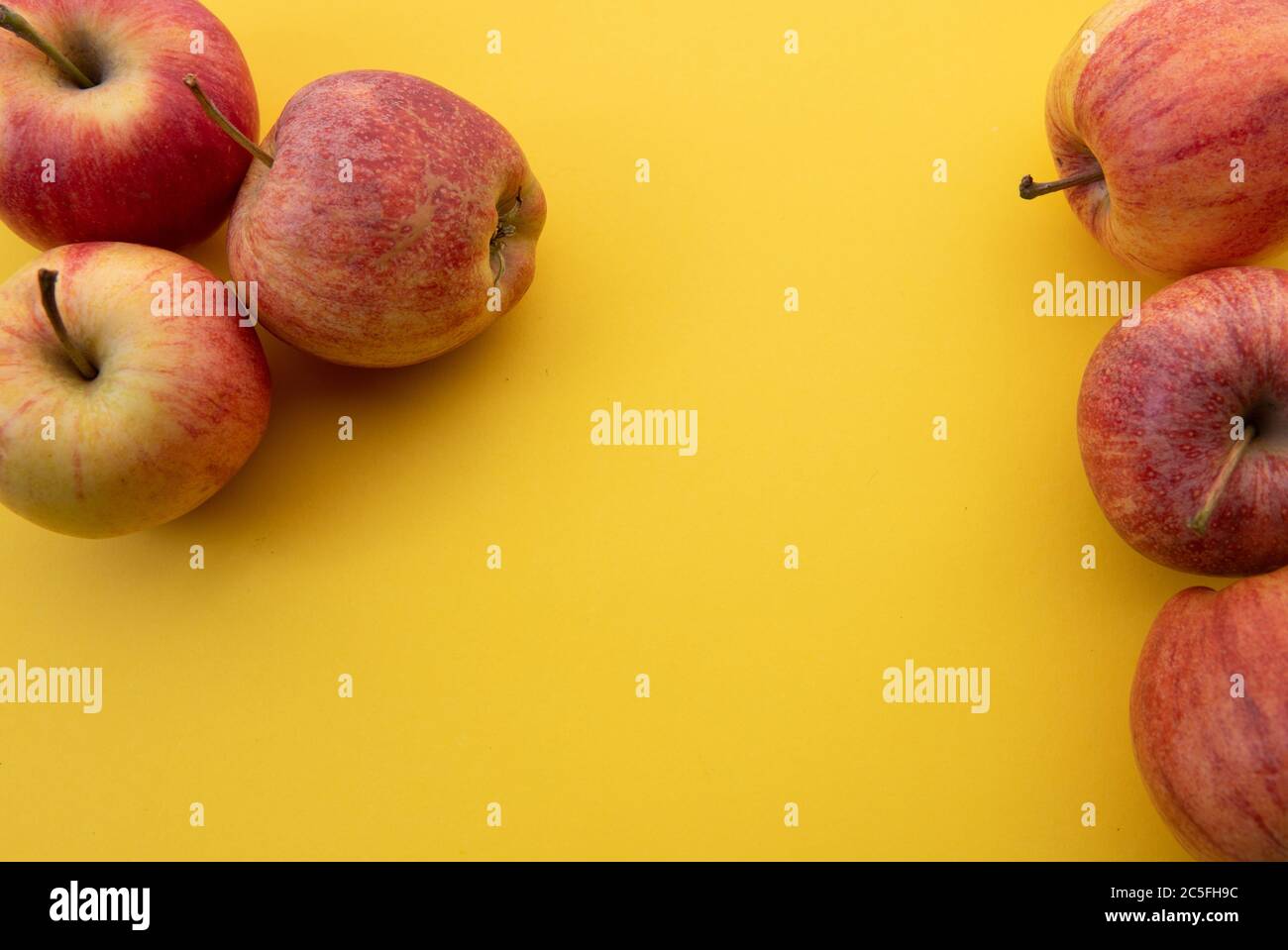 Red apples arranged side by side on a yellow background. Natural ...