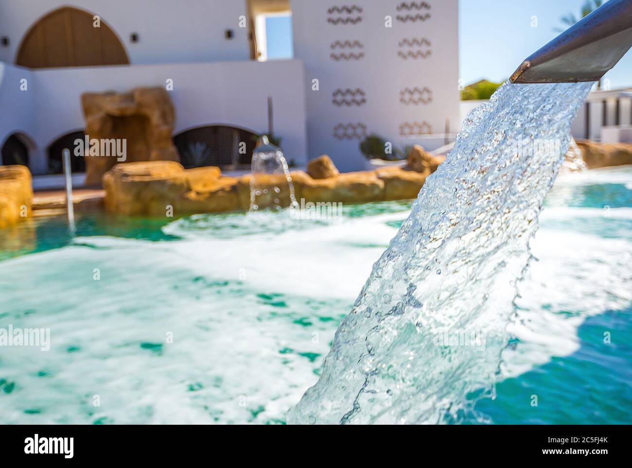 Stream water out of artificial waterfall in outdoor pool Stock Photo ...