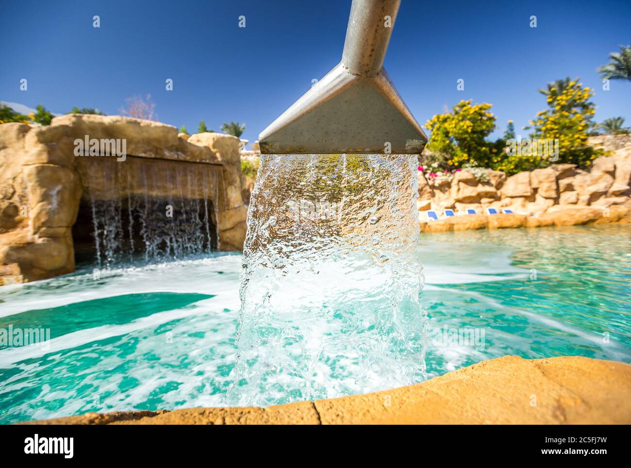 Stream water out of artificial waterfall in outdoor pool Stock Photo ...