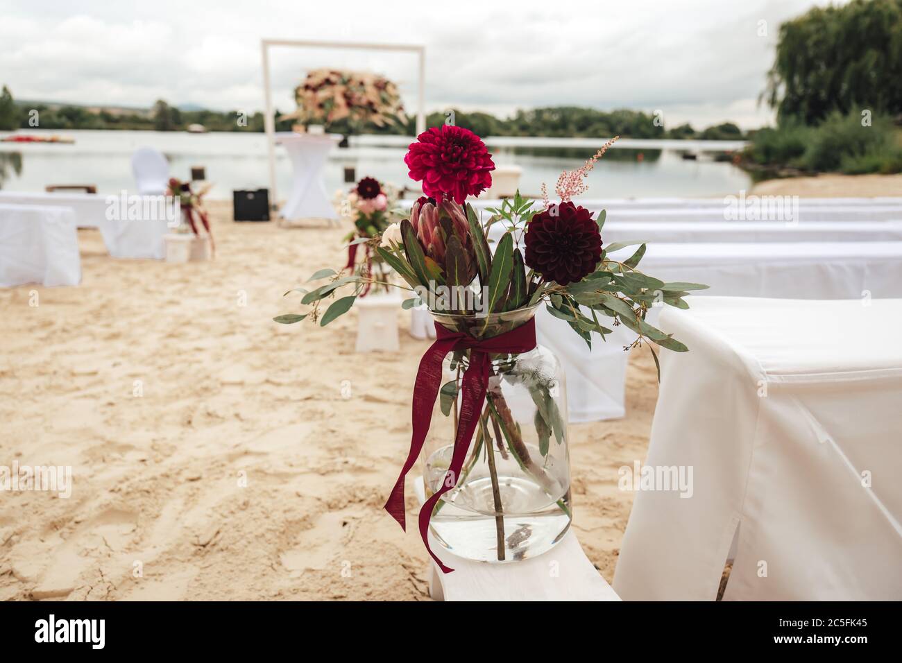 Dark red dahlia flowers in transparent glass vase. Outdoor wedding ...