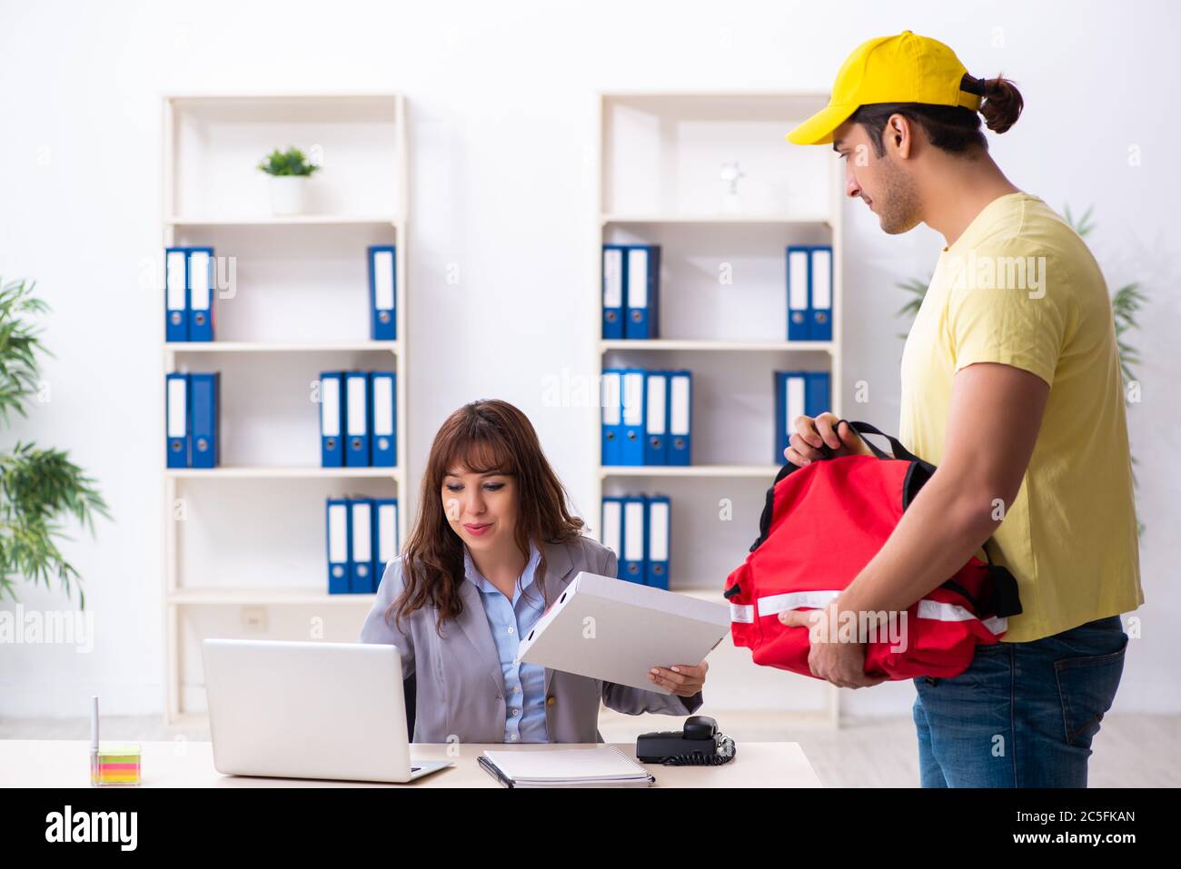 Young courier delivering pizza to the office Stock Photo - Alamy