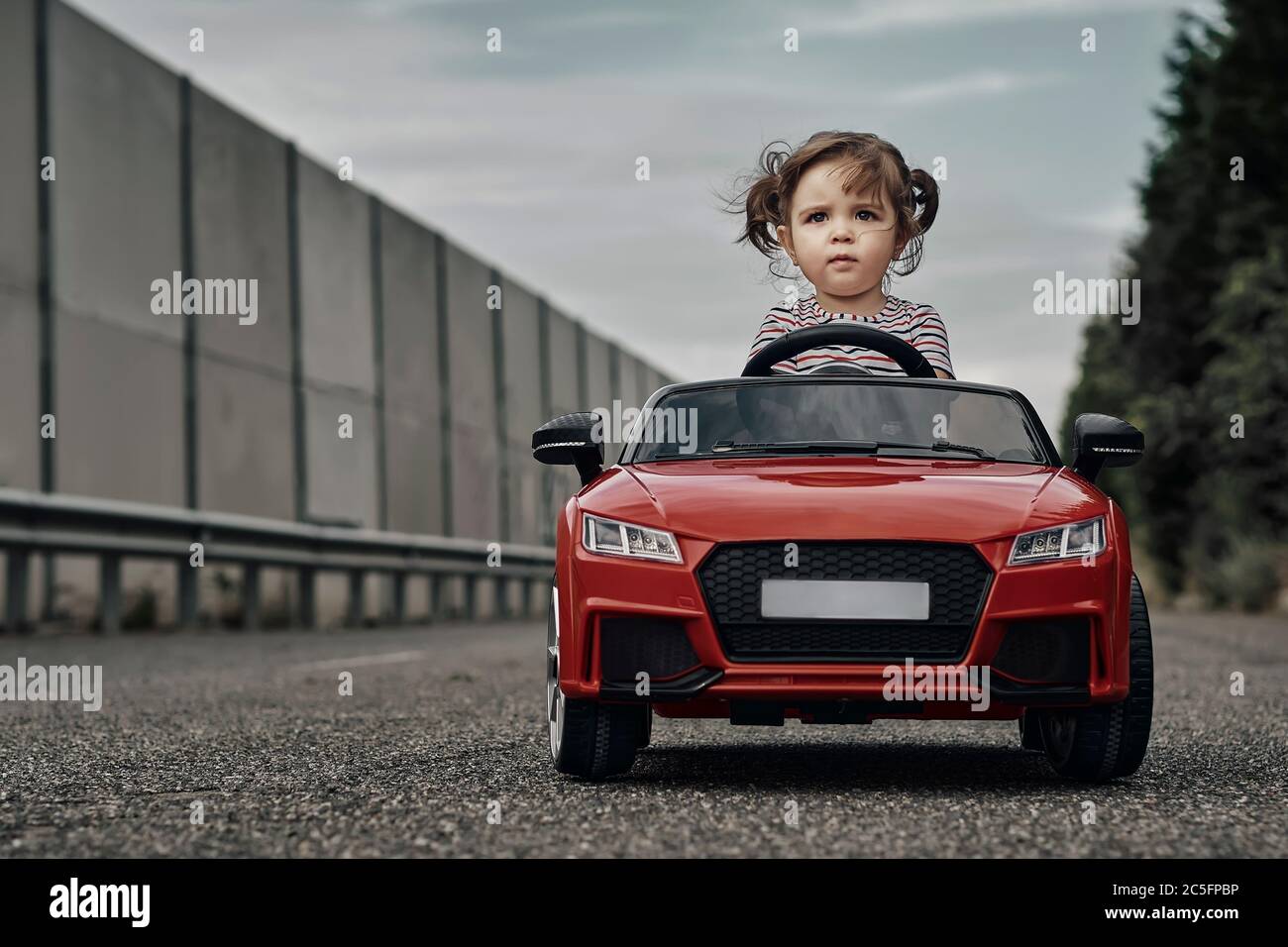 An 18-month-old girl riding in a red toy car Stock Photo - Alamy