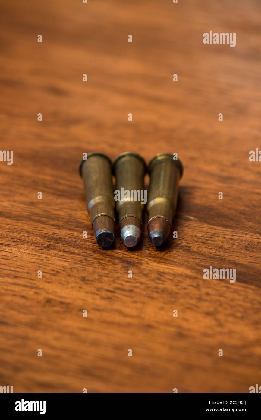 Three bullets laying on wooden background Stock Photo - Alamy