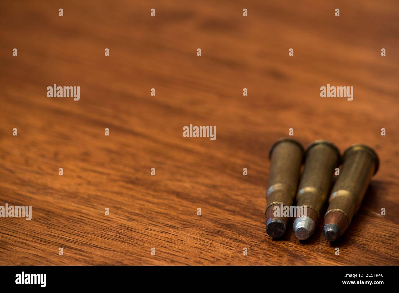 Three bullets laying on wooden background Stock Photo - Alamy